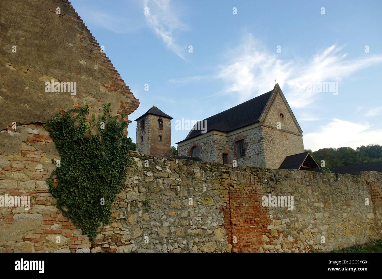Medieval monastery with beautiful blue sky, stone wall and green bush ...