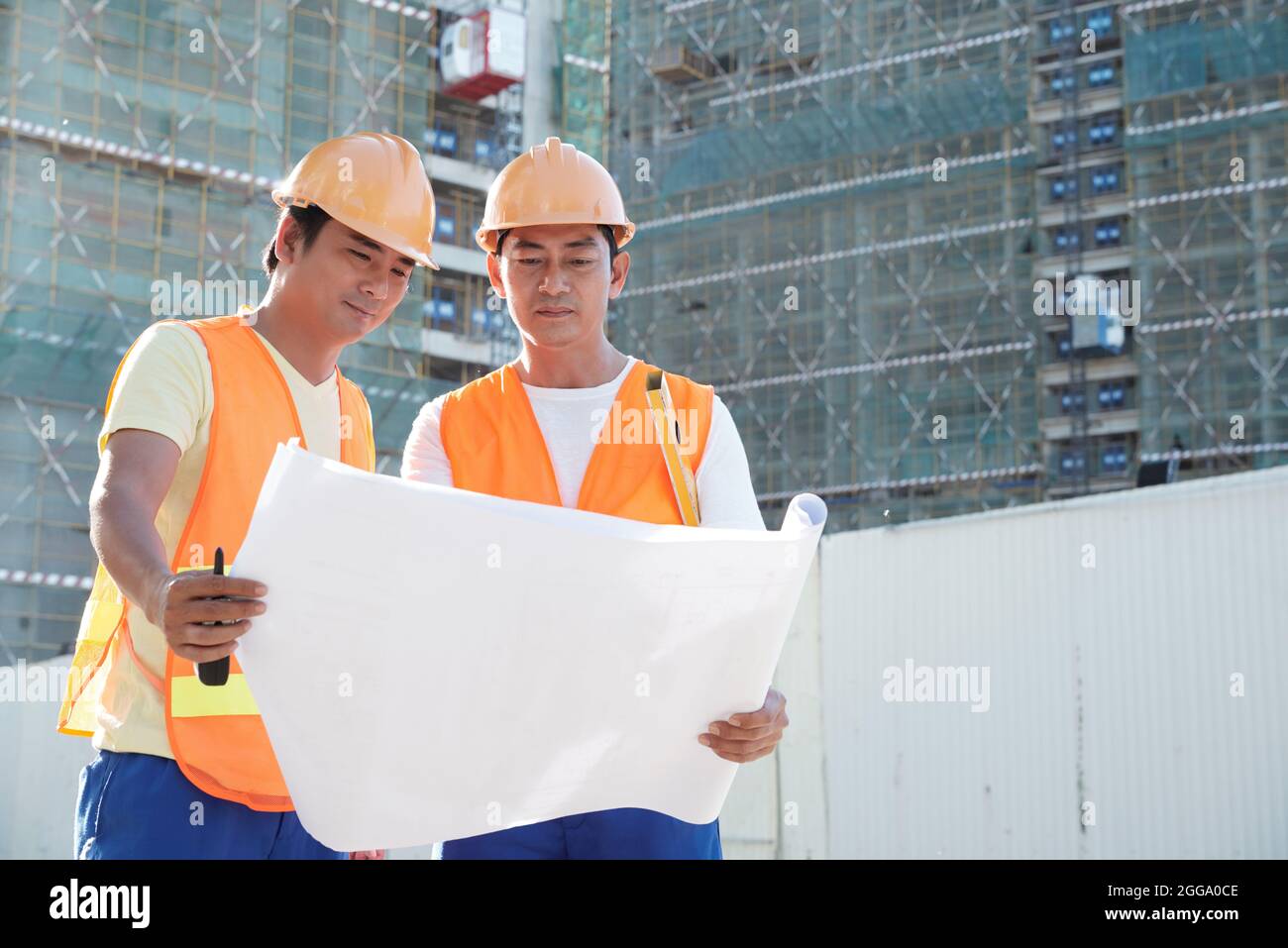 Team of construction workers discussing details of building plan when ...