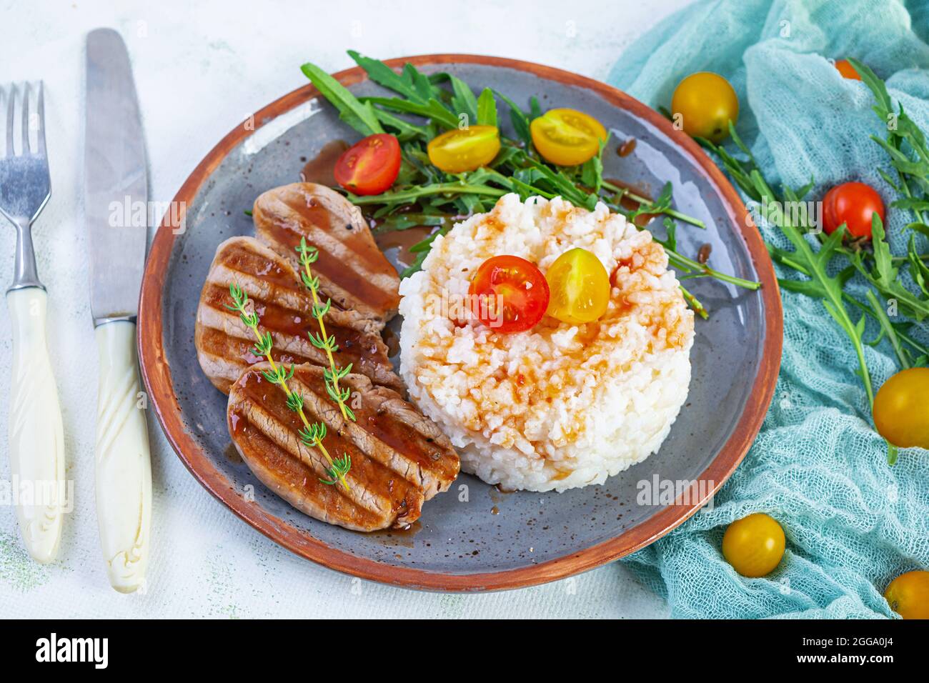 Rice with grilled pork meat, tomatoes and green herbs on white ...