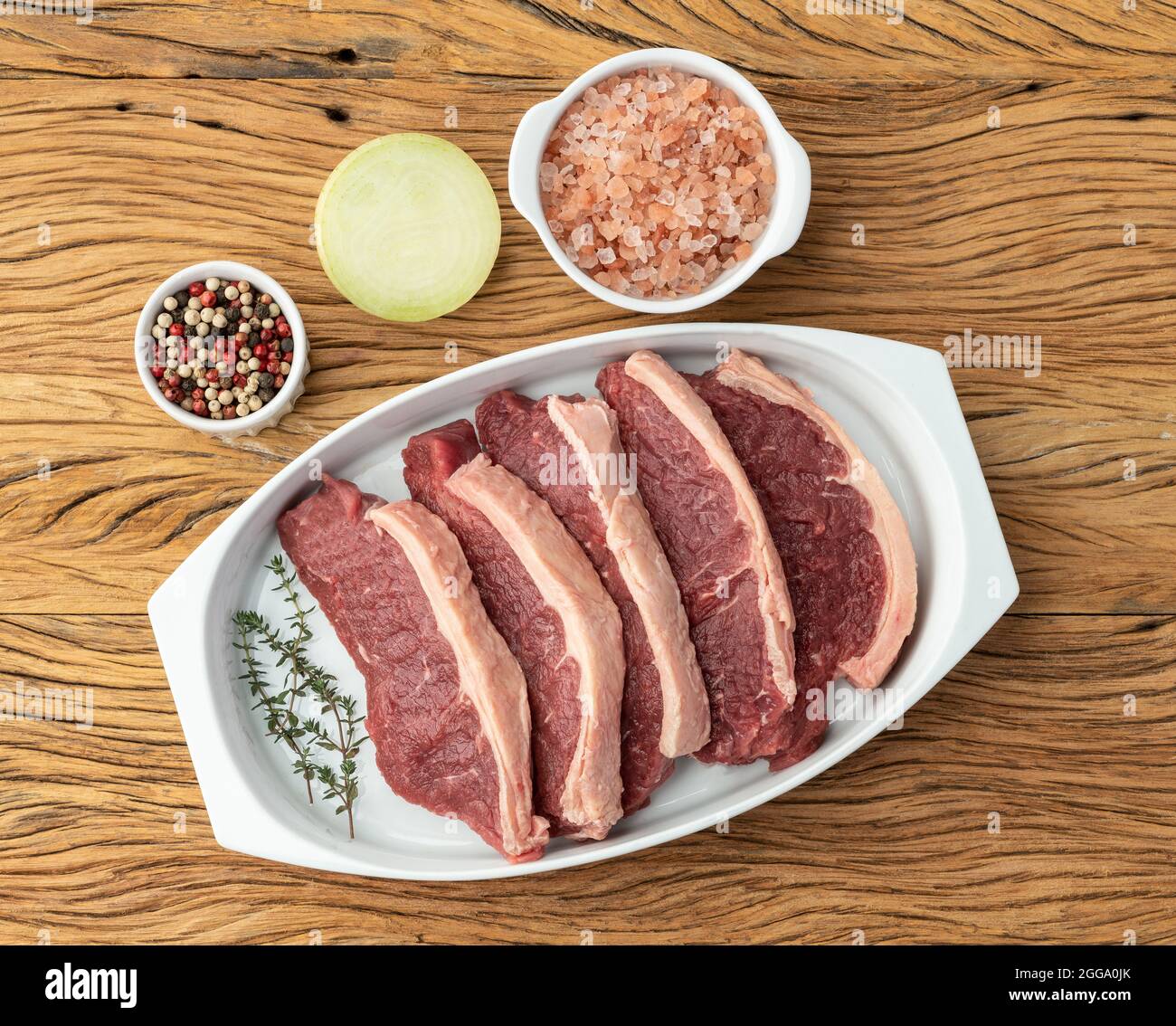Sliced raw strip loin meat over white plate with seasonings Stock Photo ...