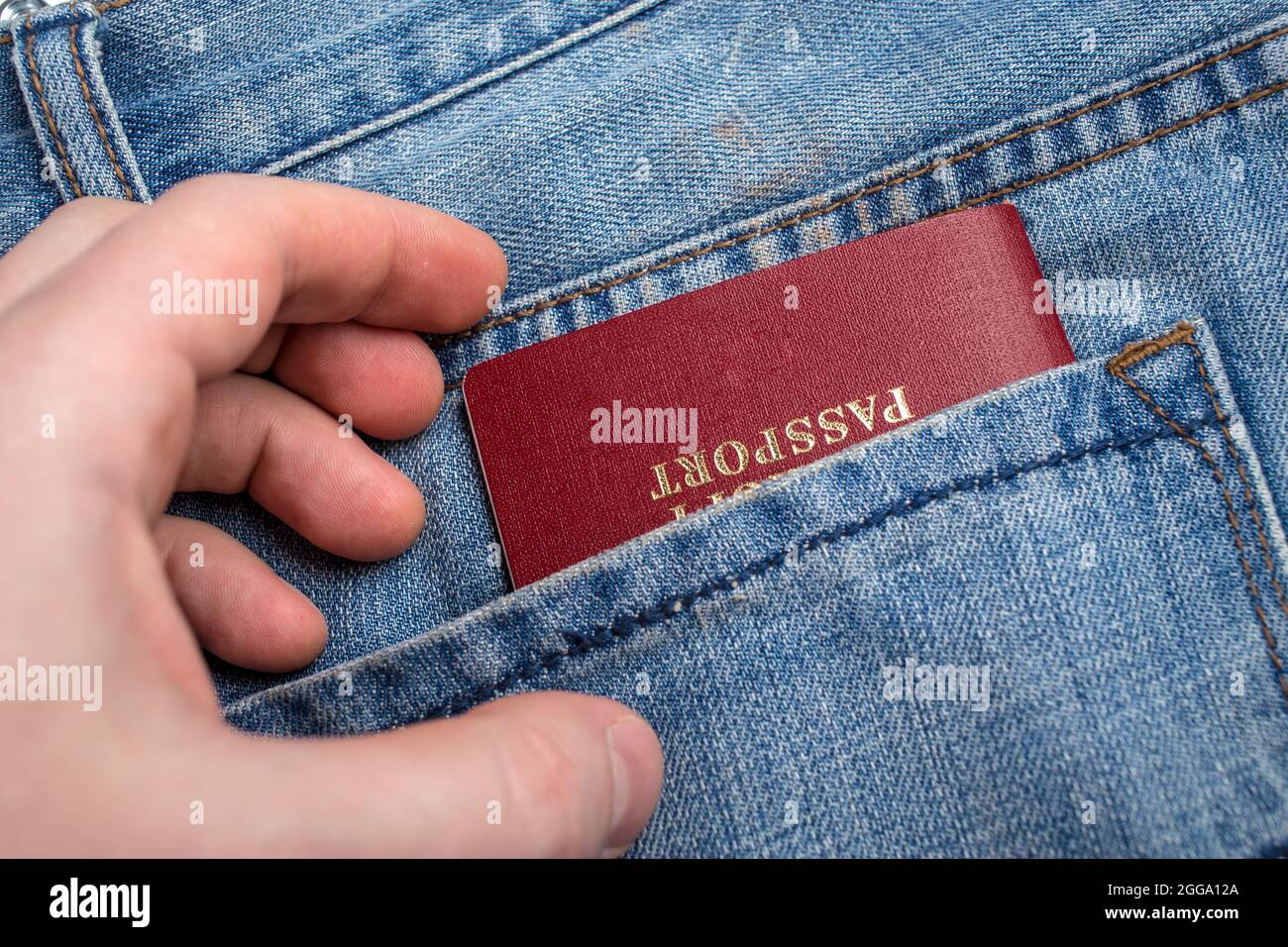 Hand gets passport back pocket of jeans. Top view Stock Photo - Alamy