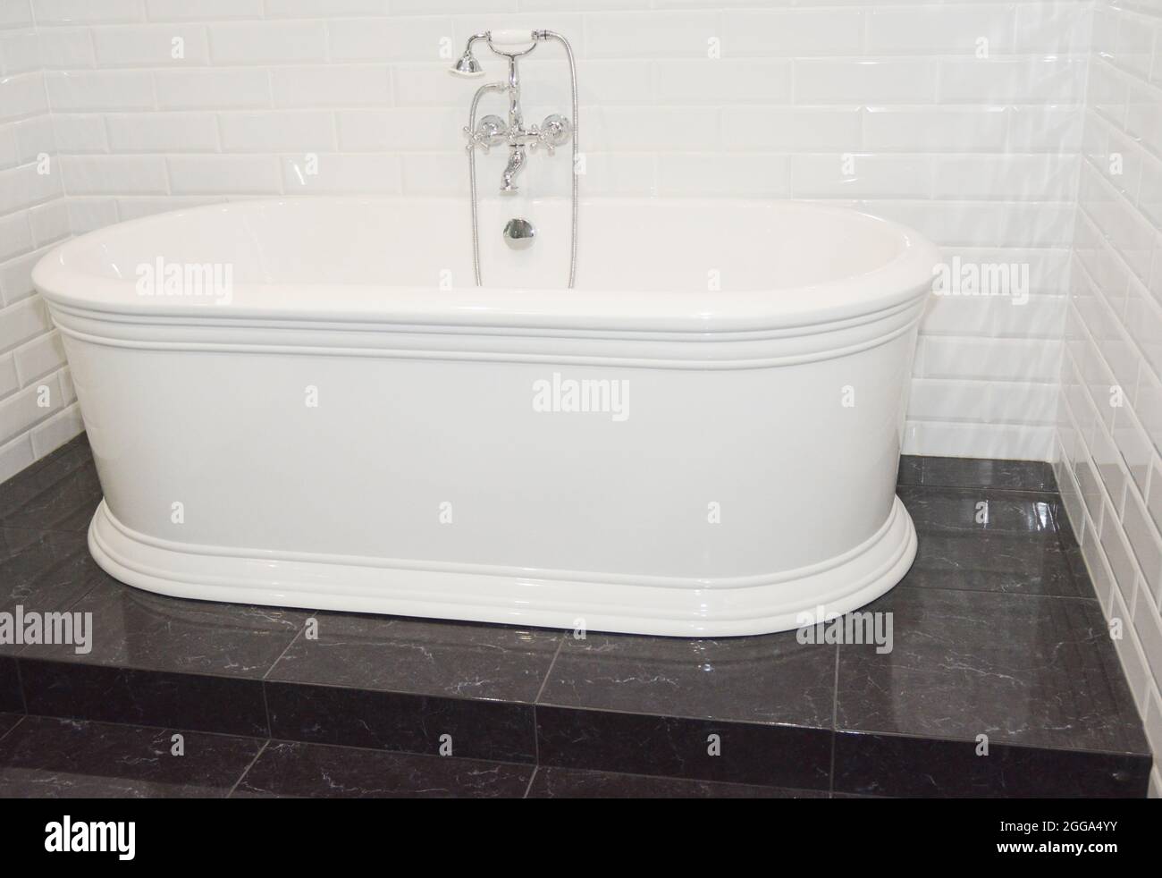 A white luxurious buthtub on a black raised marble platform with a ...