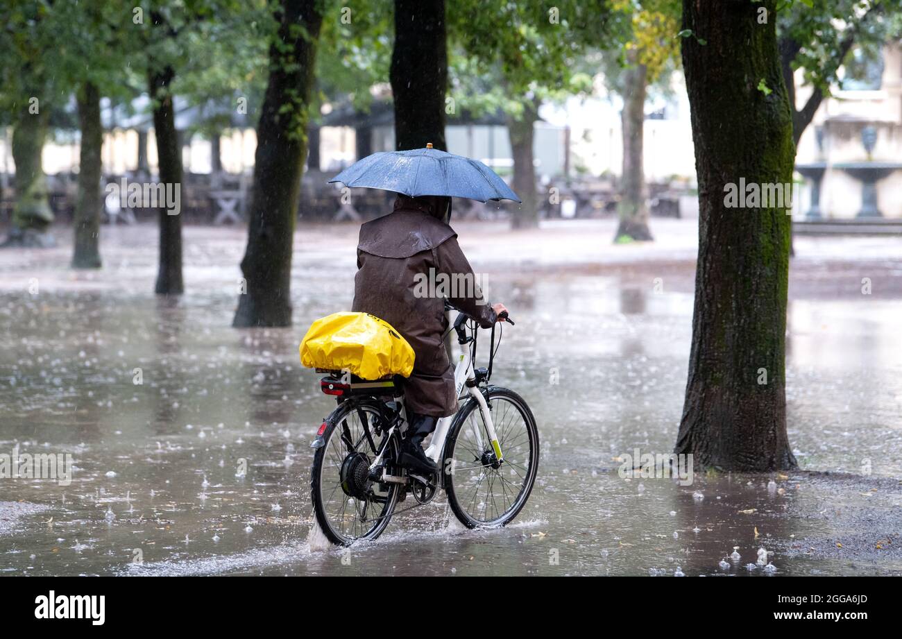 Munich, Germany. 30th Aug, 2021. A woman rides her bicycle through the ...