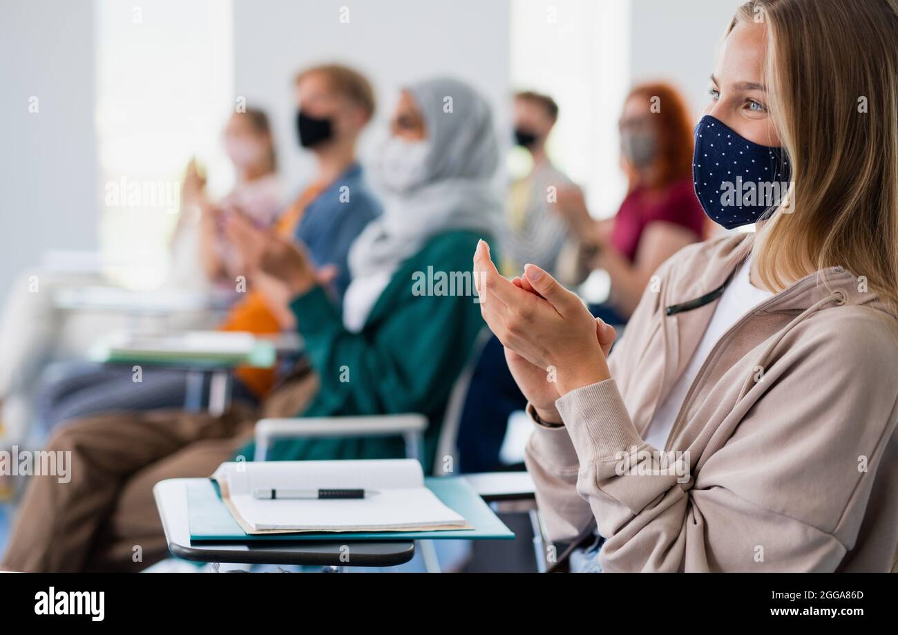 University students clapping in classroom indoors, coronavirus and back ...