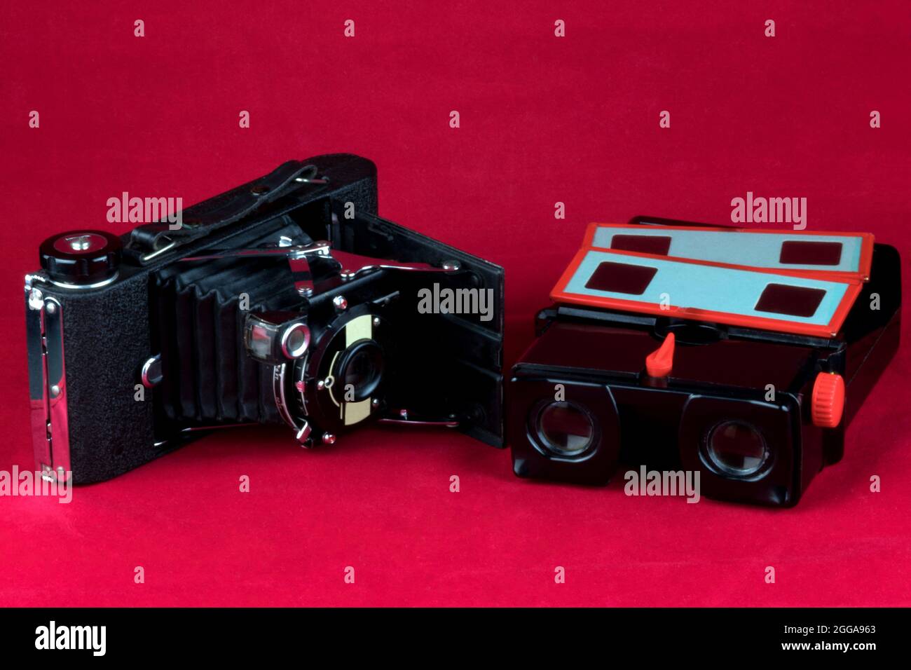 Ancient film camera and old slide viewer isolated on a red background ...