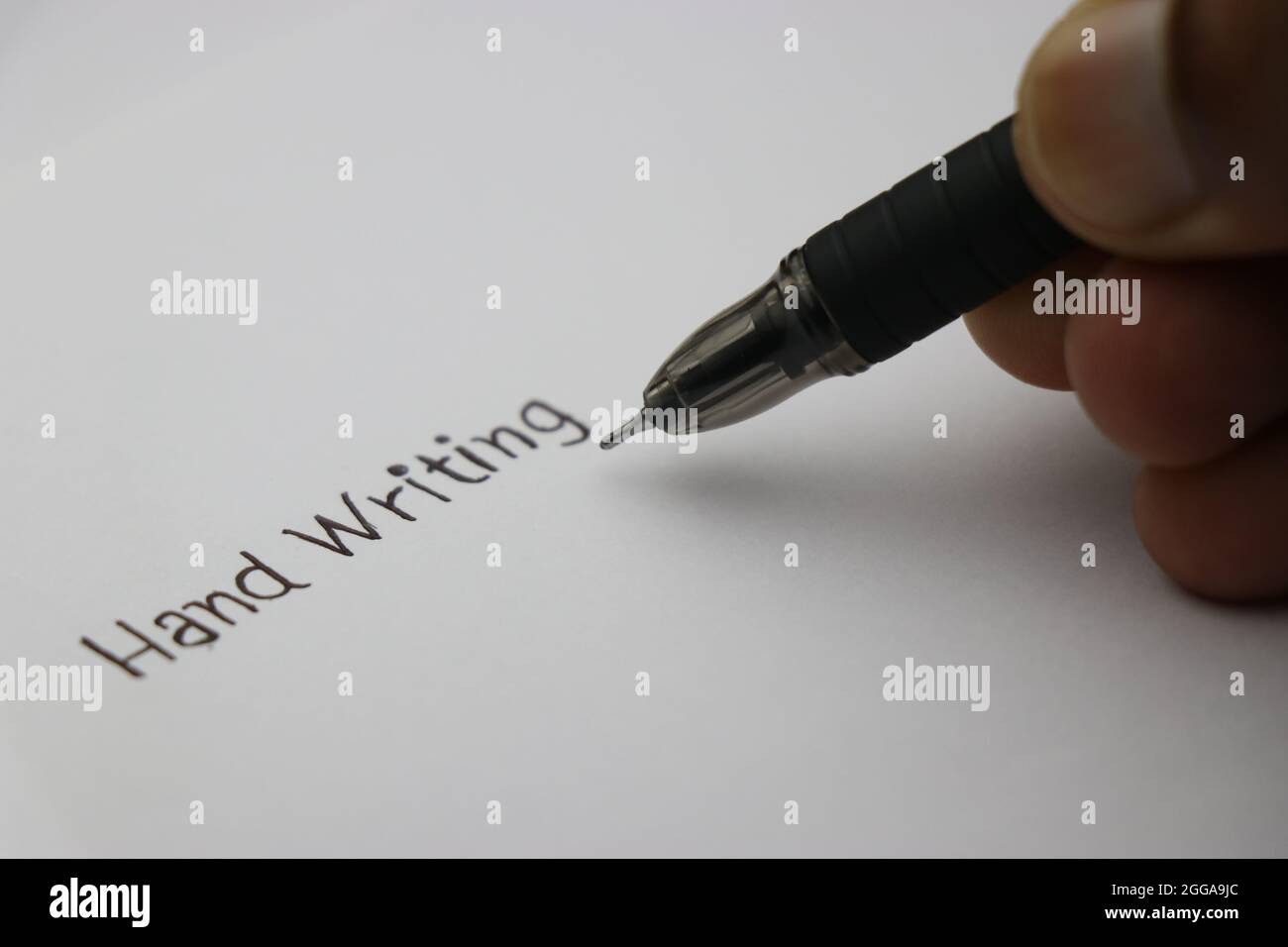 Hand writing being written on plane sheet of paper by black pen ...
