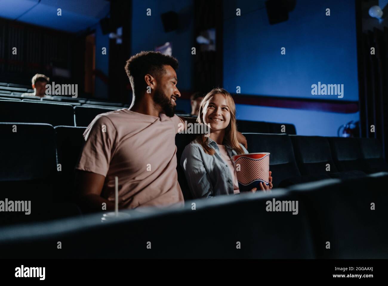 Cheerful young couple in love in the cinema, watching film Stock Photo ...