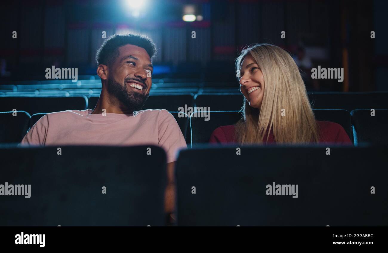 Front view of cheerful young couple in the cinema, watching film and ...