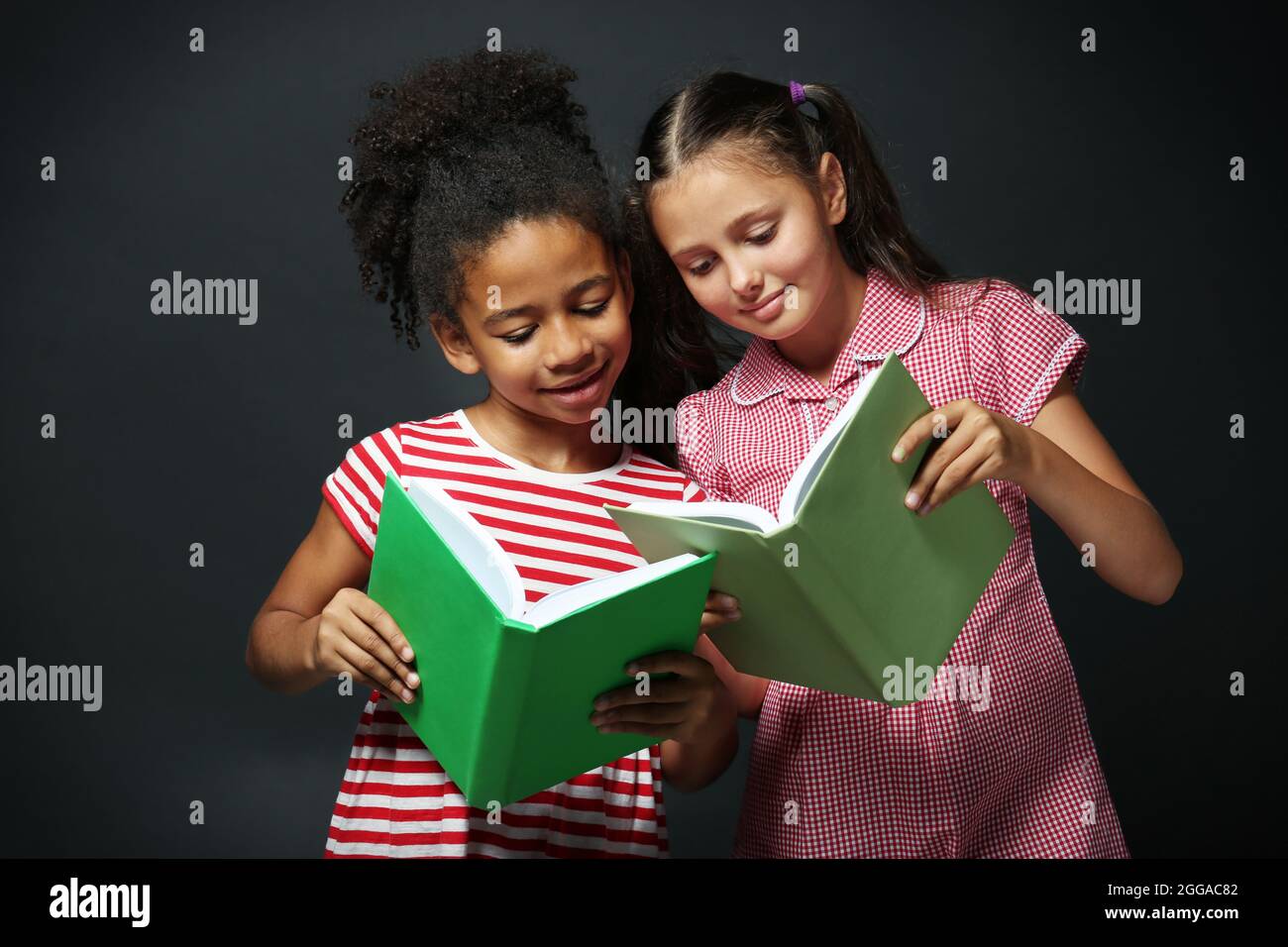 Cute girls reading book on grey background Stock Photo - Alamy
