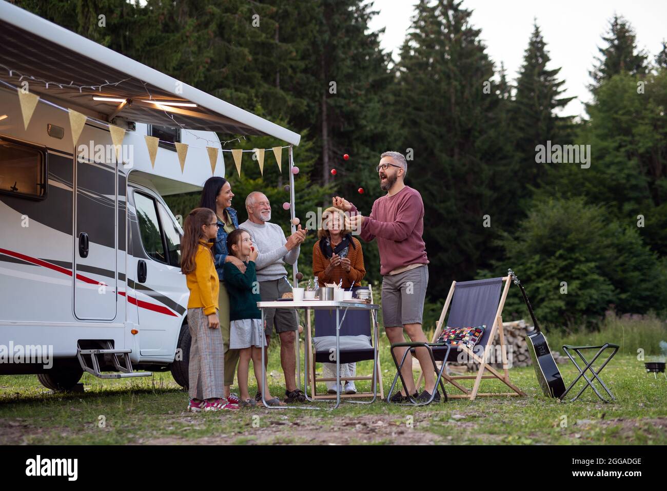 Multi-generation family standing and having fun outdoors by car ...