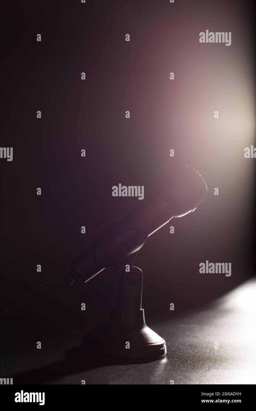 Black microphone on table holder on black background with stage light ...