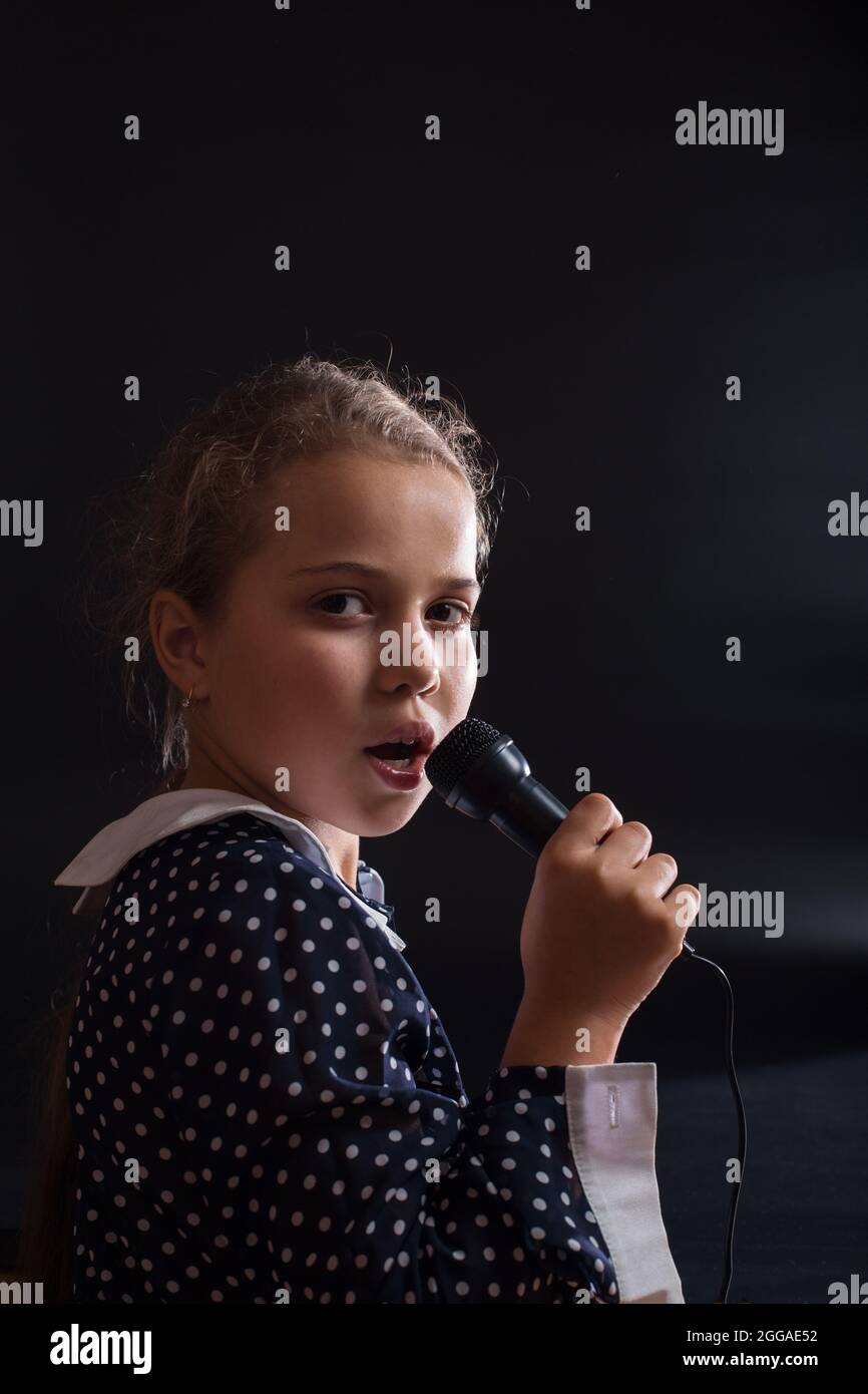 Cute little girl sing with microphone on black background Stock Photo ...