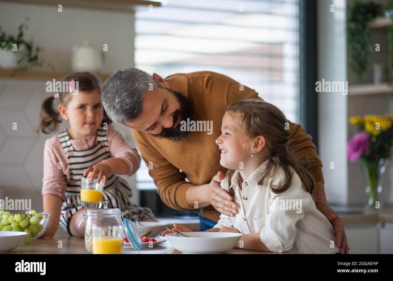 Father With Three Daughters Indoors At Home Eating Breakfast In