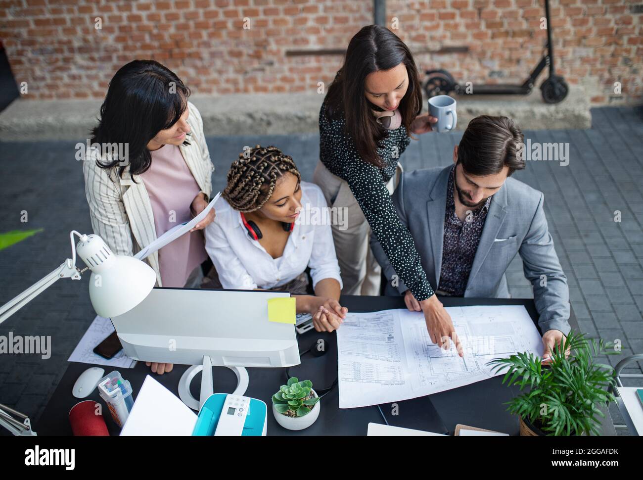 Top view of young and old architects sitting and working at desk in ...