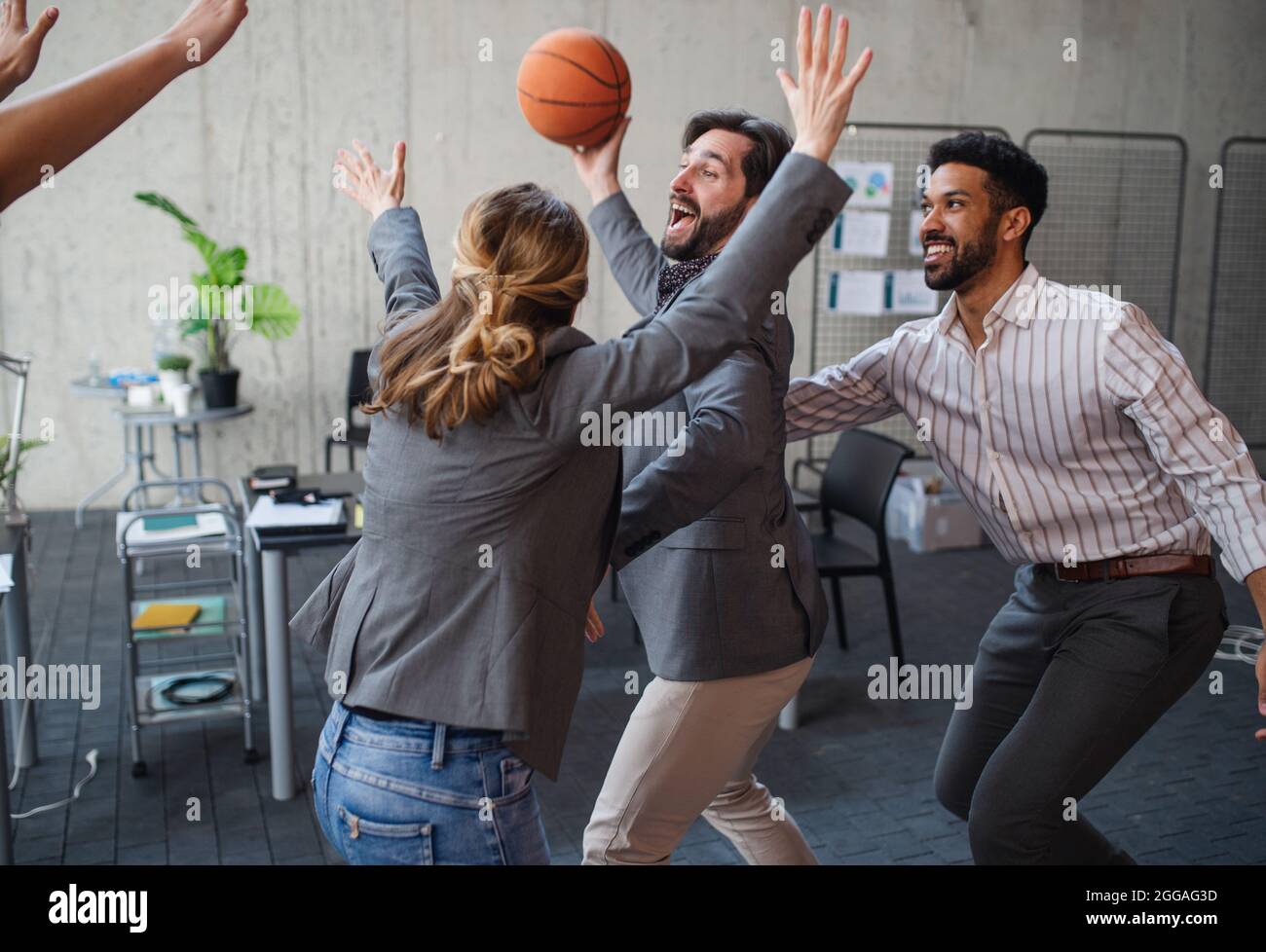Group of cheerful young businesspeople playing basketball in office ...