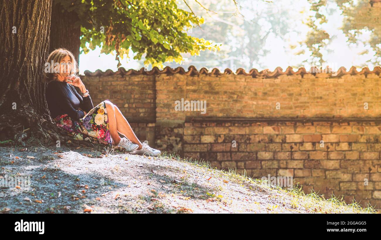 Beautiful elderly Caucasian woman sitting under a tree in daytime Stock ...