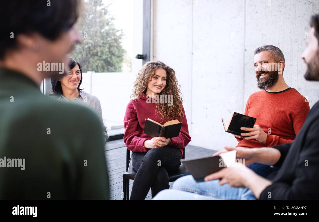 Men and women sitting in circle during group therapy, reading and ...