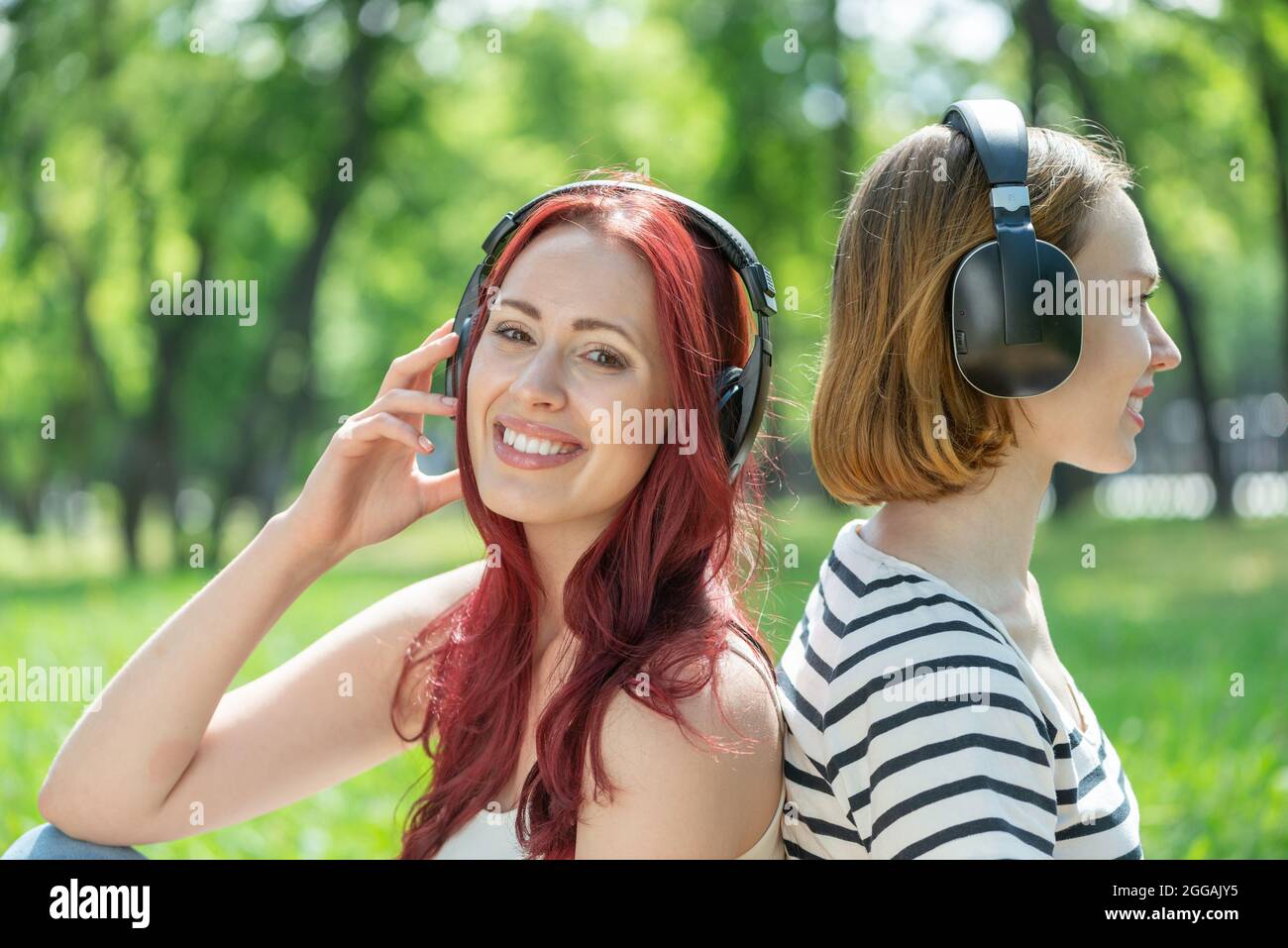 Two young girls in the park listen to music Stock Photo - Alamy