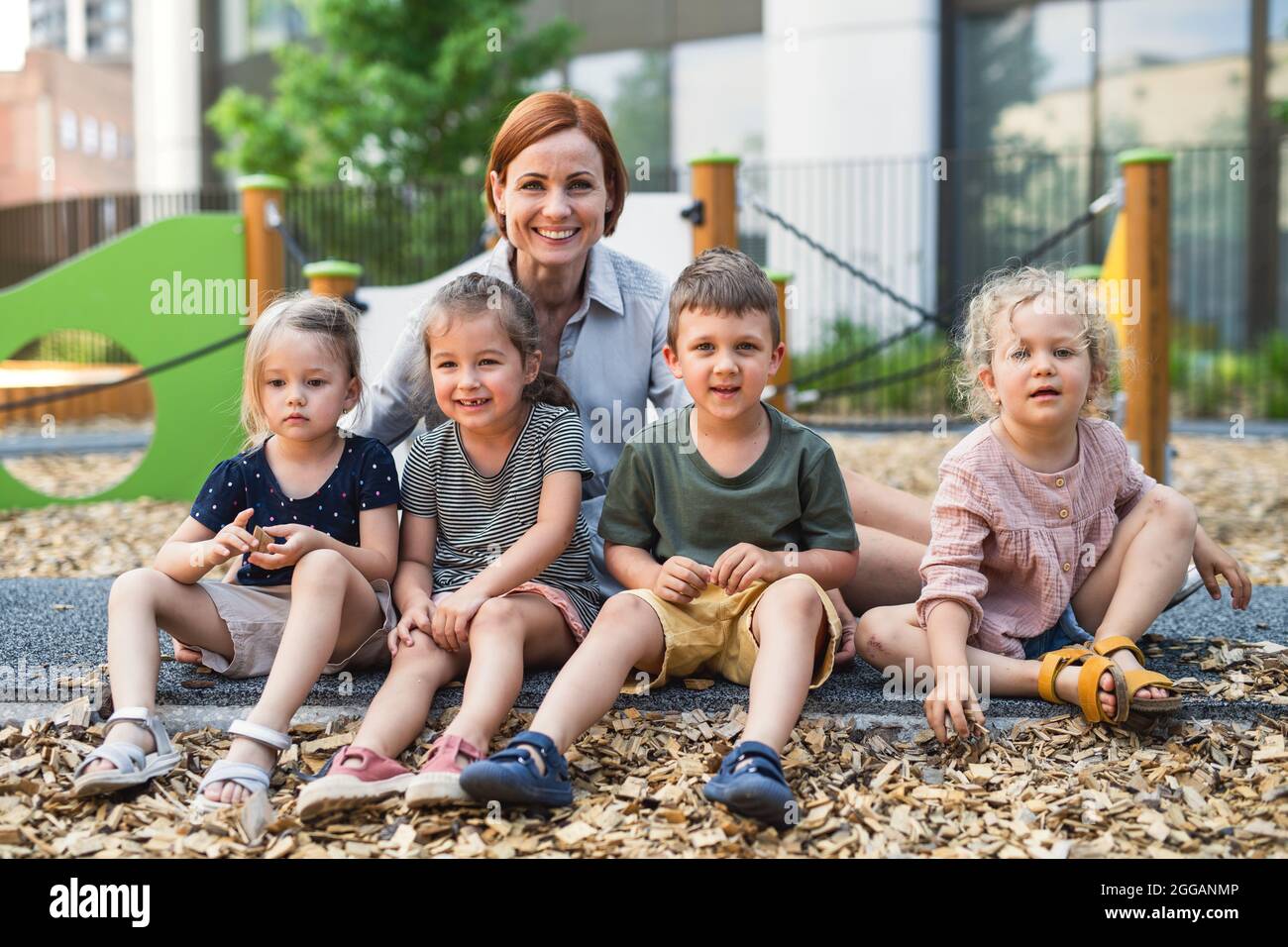 Group of small nursery school children with teacher outdoors on ...