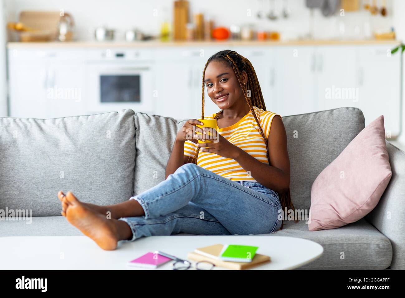 Happy black woman sitting on couch at home, drinking coffee Stock Photo ...