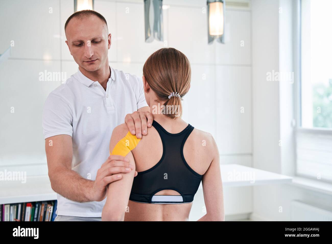 Young woman in black sport bra getting manual therapy with kinesiology ...