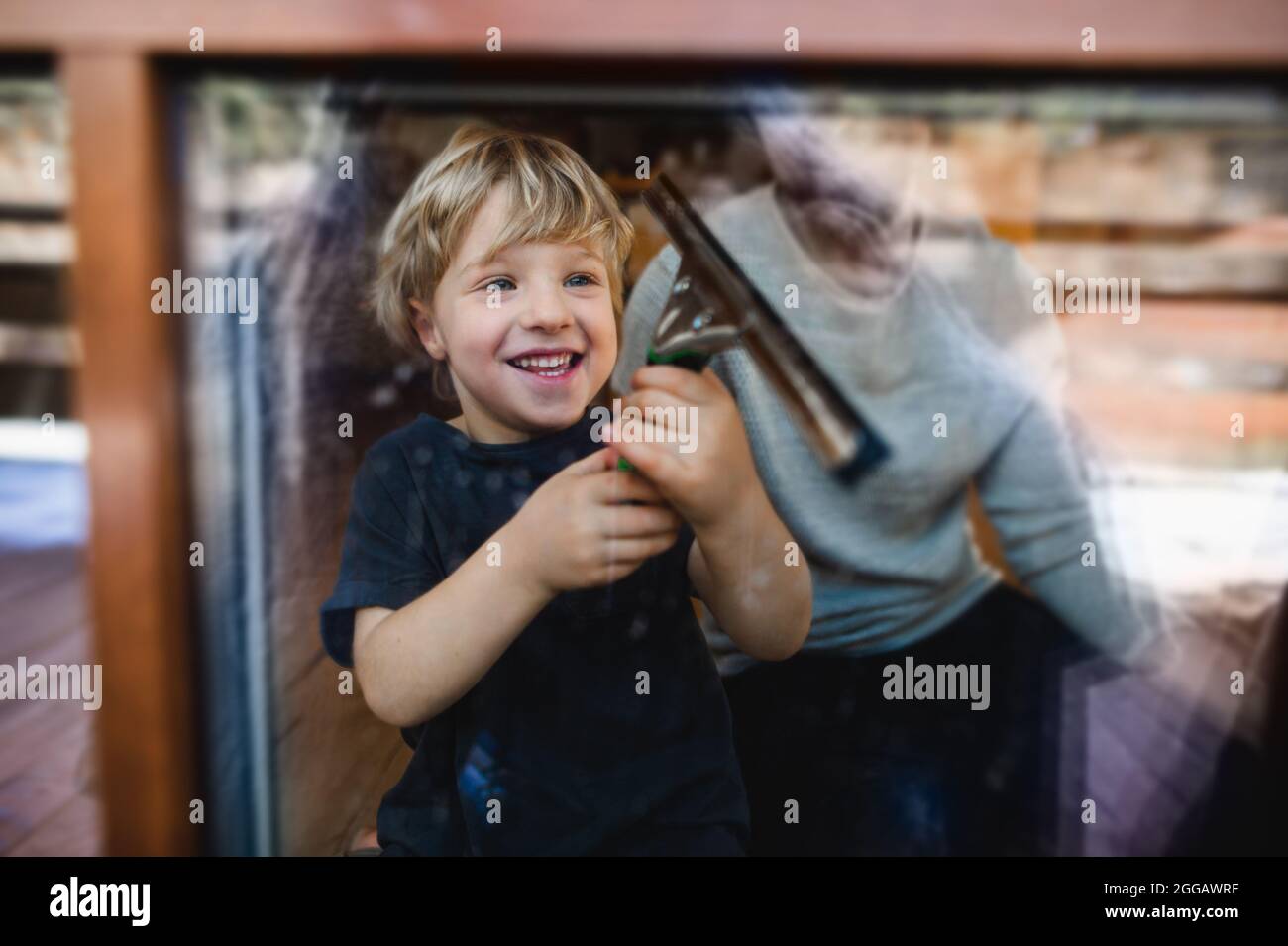 Happy boy with unrecognizable father cleaning windows at home, daily ...