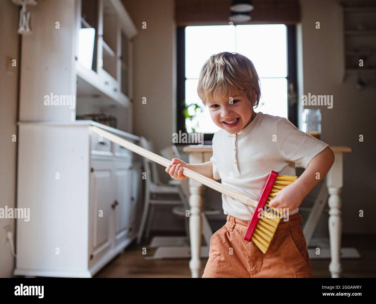 Small boy with broom helping with housework indoors at home, having fun ...