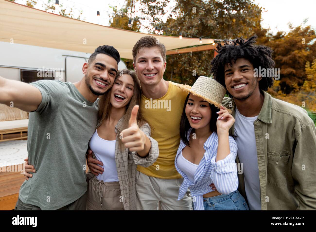 Diverse millennials taking selfie together near camper van, smiling at ...