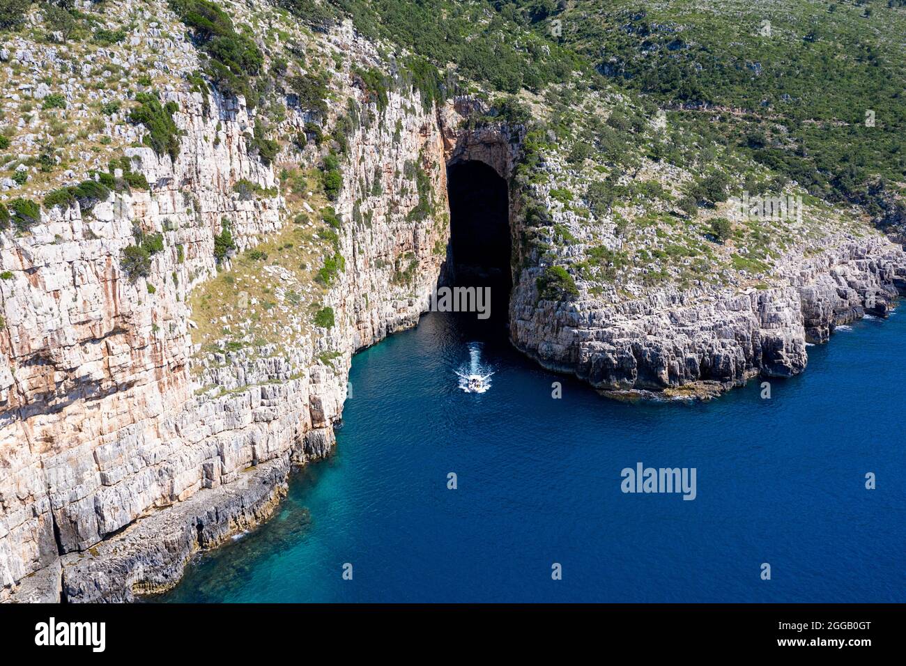 Aerial view of spectacular Haxhi Ali Cave and a tourist boat leaving it ...