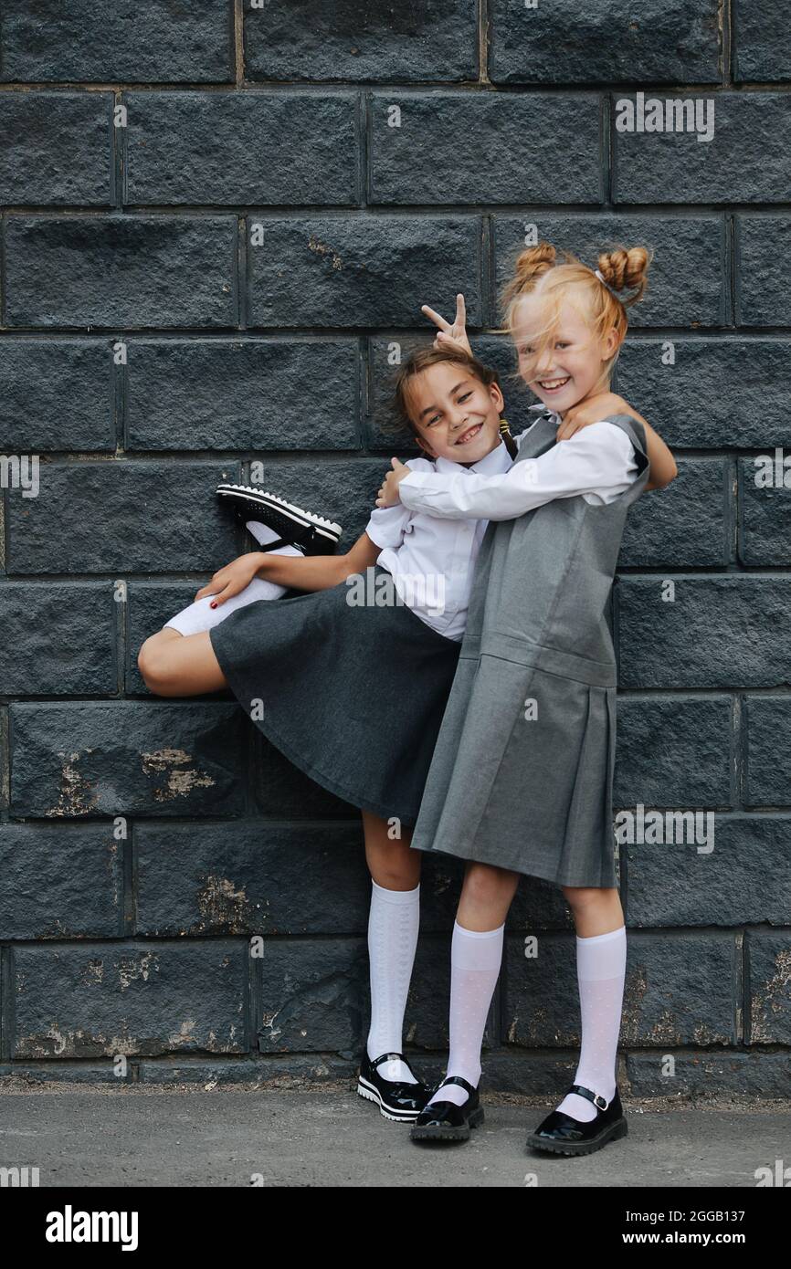 Portrait of two cute little schoolgirl friends. One is lifting her leg ...