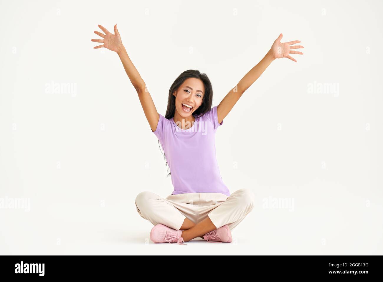 Smiling young asian woman raised arms up screaming and celebrating ...