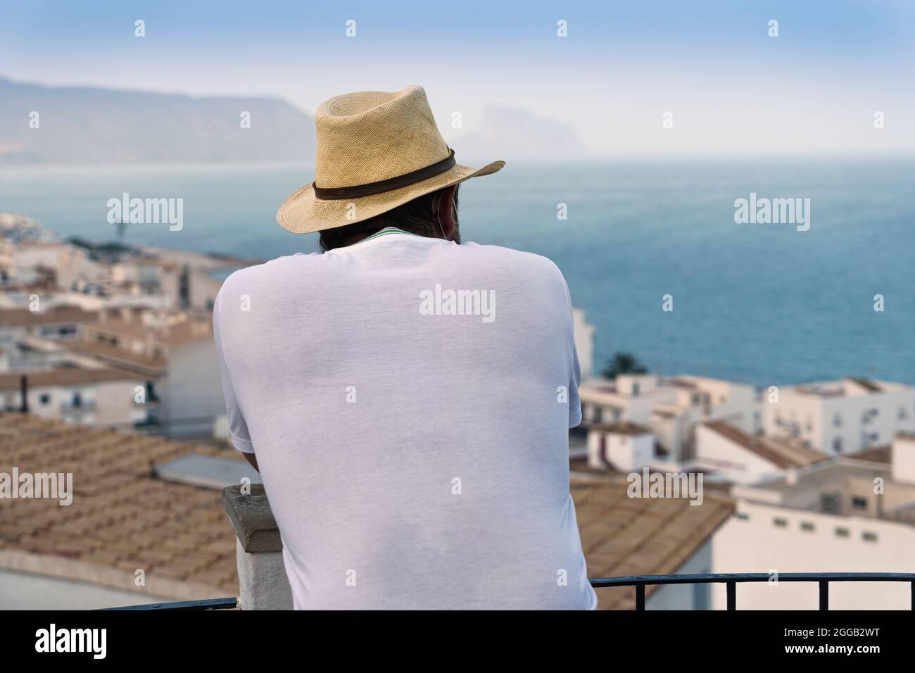 Man with his back turned and wearing a hat looking at a landscape of a ...