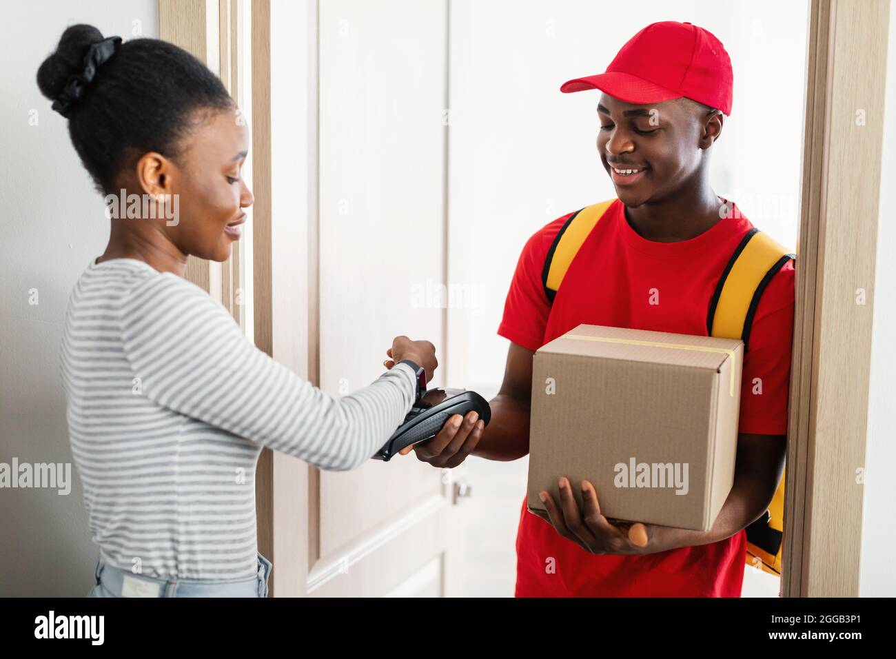 African Woman Receiving Box From Deliveryman Paying Using Smartwatch ...