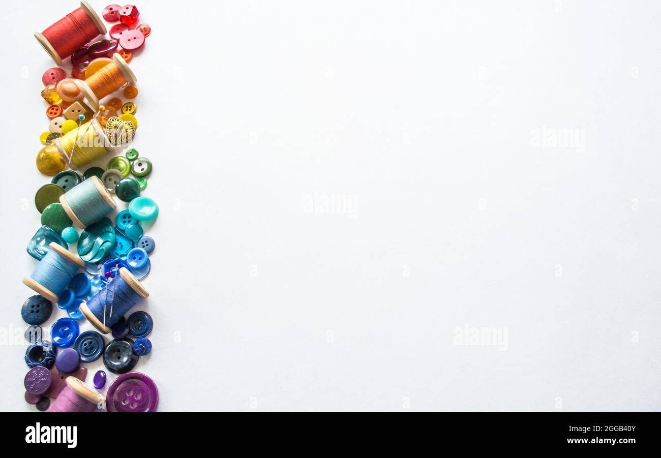 A lot of buttons and reels with colorful threads, laid out on a white ...