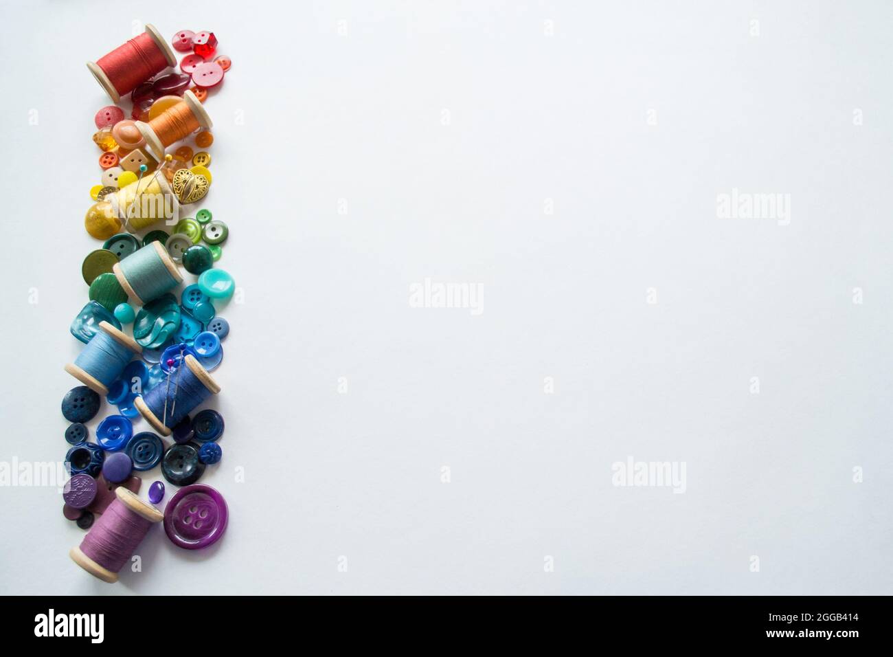 A lot of buttons and reels with colorful threads, laid out on a white ...