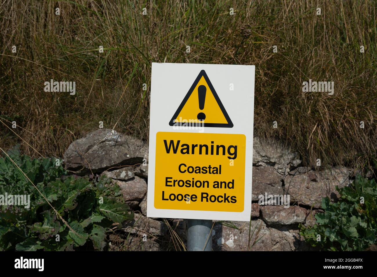 Yellow, black and white sign: Warning coastal erosion and loose rocks ...