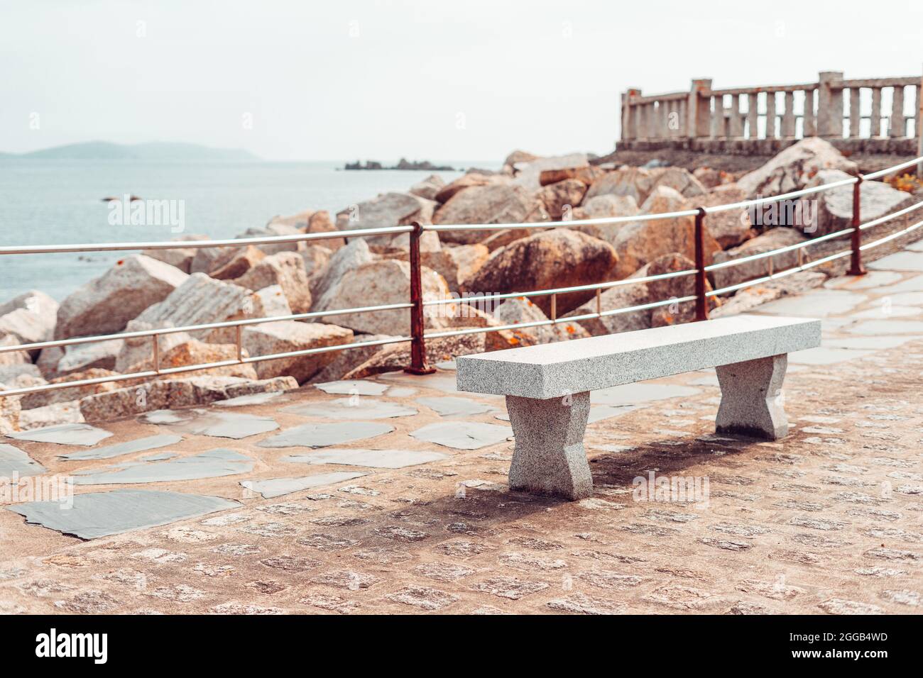 Bench on a viewpoint over a seawall near the ocean Stock Photo - Alamy