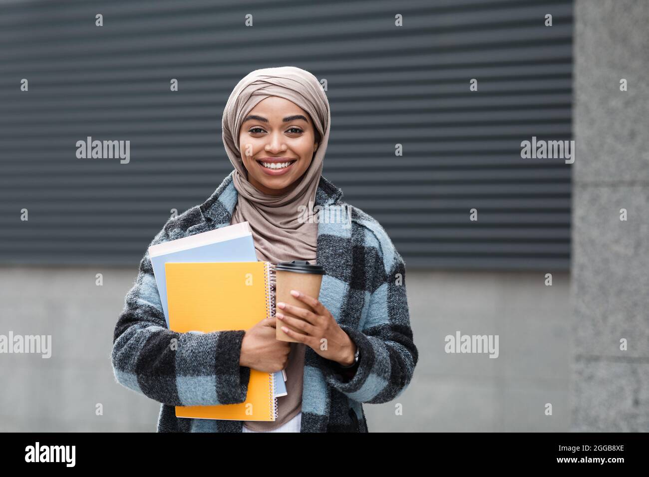 Young student lady smiling to camera, holding folder at city Stock ...