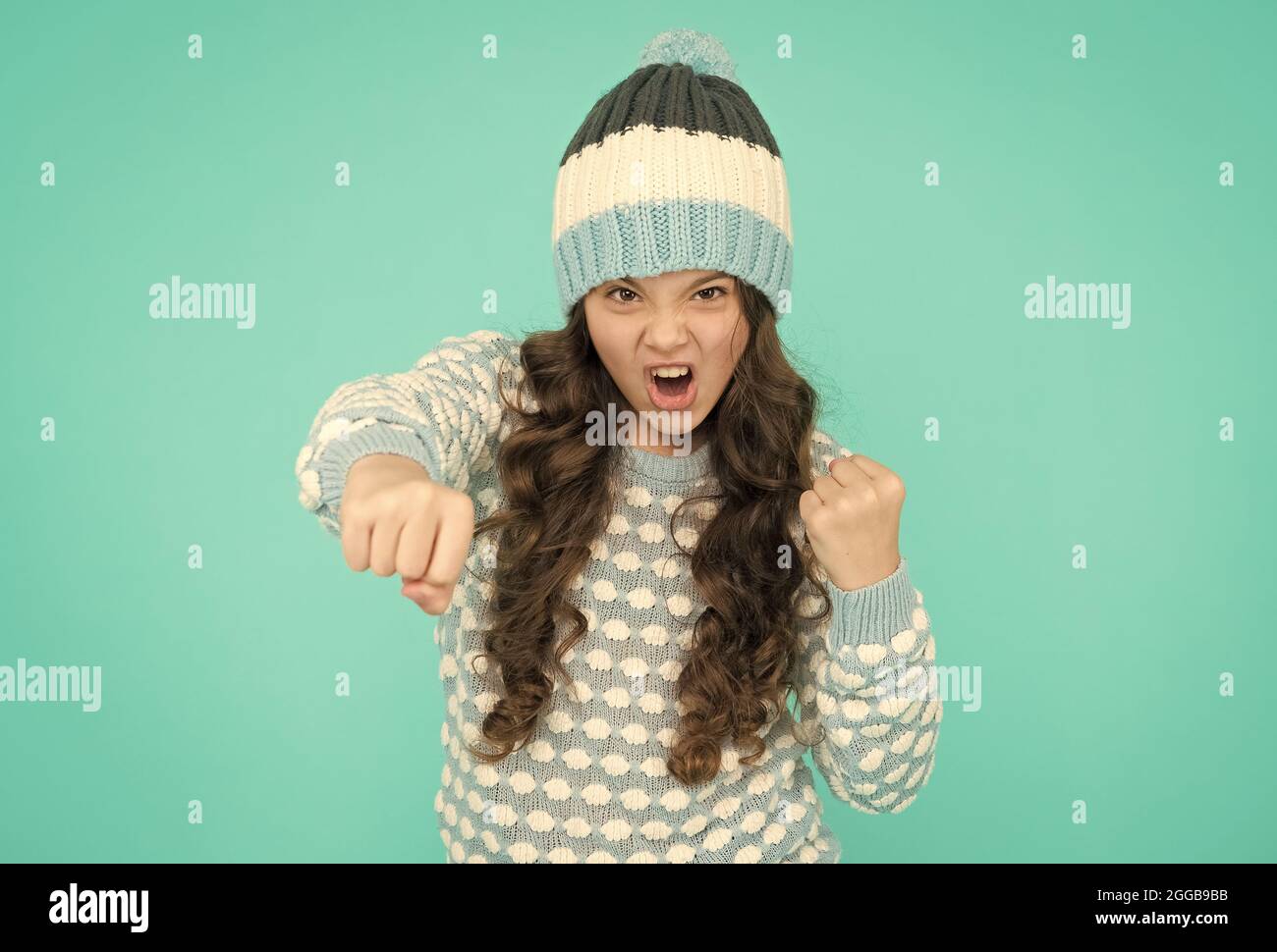 child girl with aggressive face punching with fists in knitted warm ...
