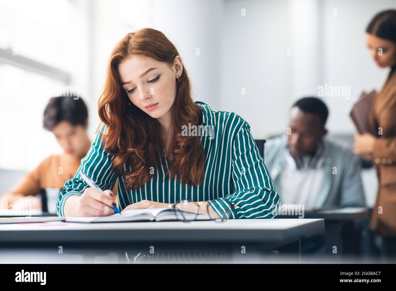 Diligent student sitting at desk in classroom posing at camera Stock ...