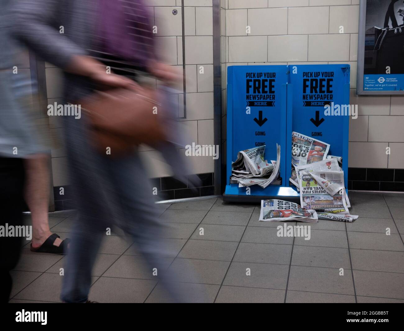 commuters walk past bin for free London Metro newspapers in London ...