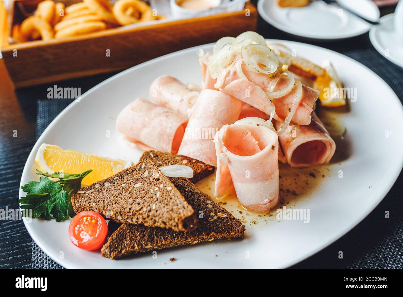 Slices of fresh-frozen fish on a plate served with grilled bread, onion ...