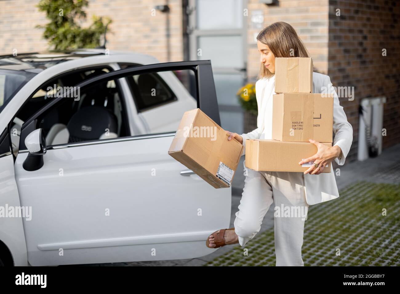 Woman with parcels near her car and home Stock Photo - Alamy