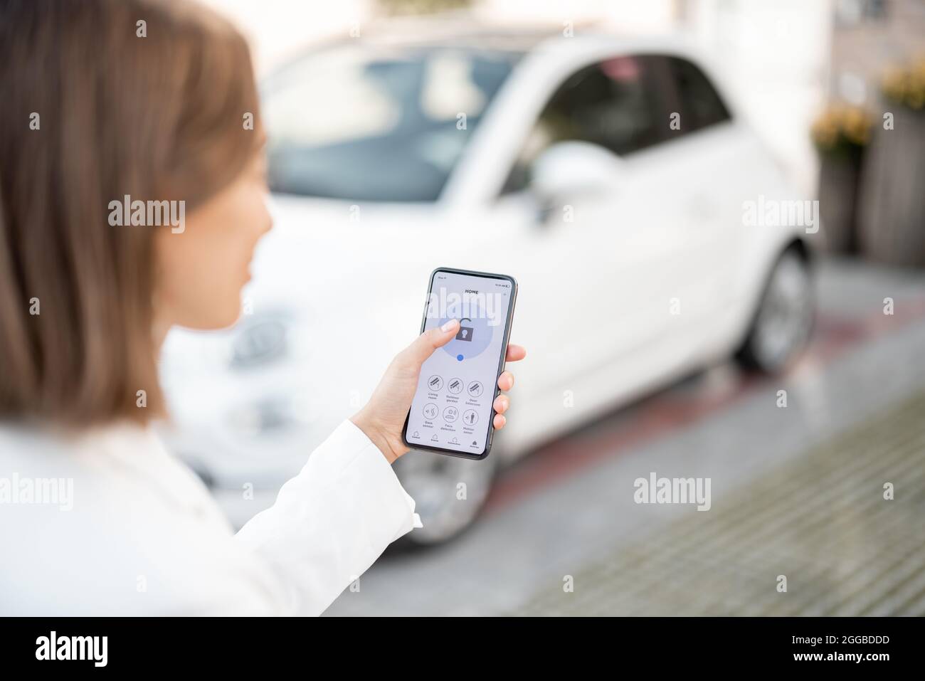 Woman control car alarm with mobile phone Stock Photo - Alamy