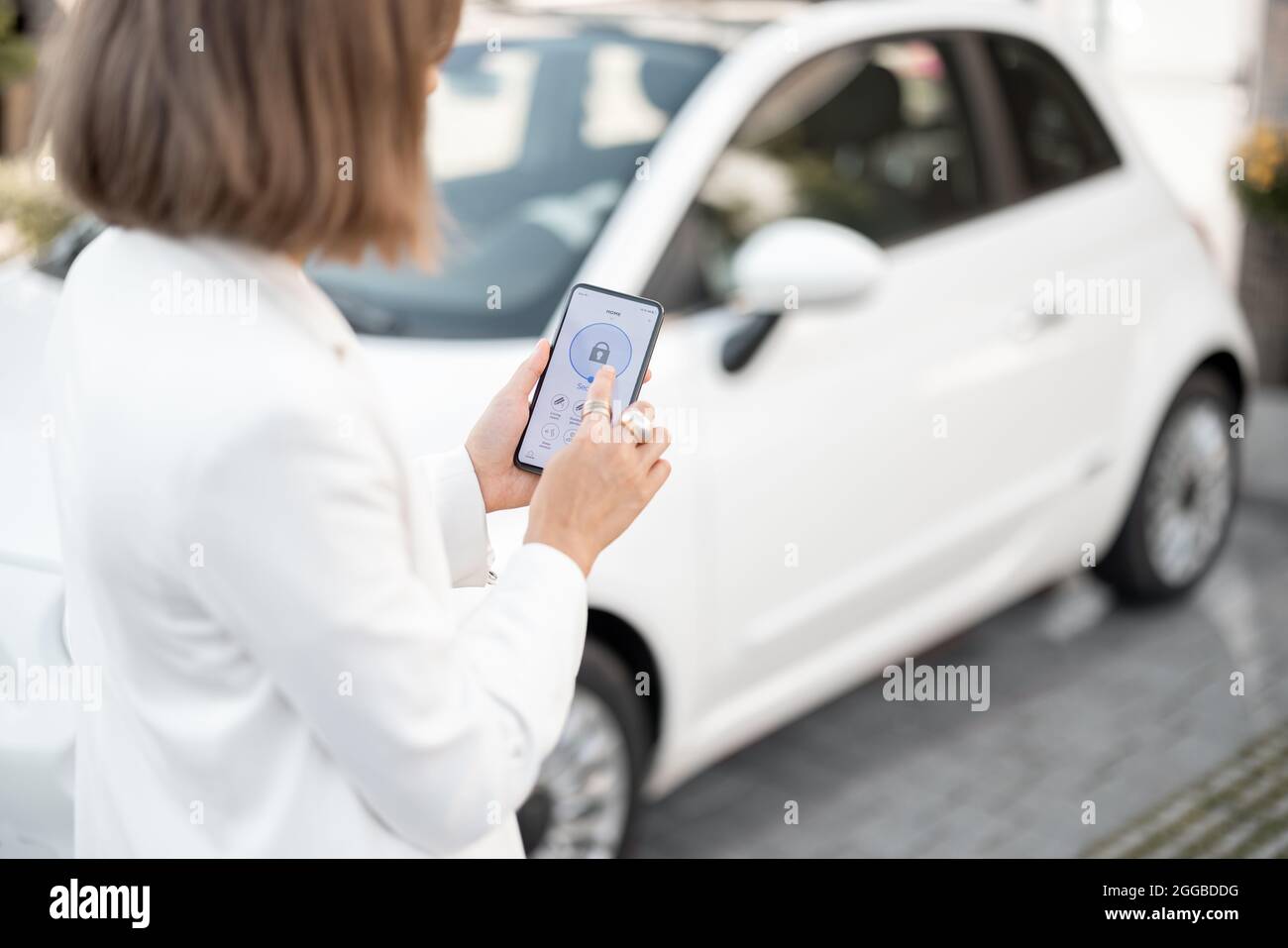 Woman control car alarm with mobile phone Stock Photo - Alamy