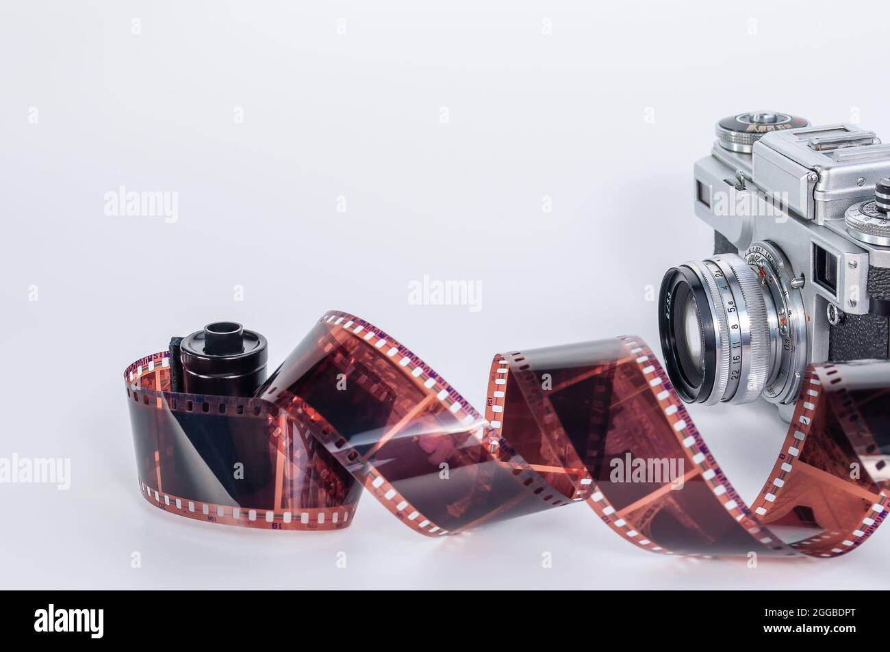 still life with retro analog camera, camera roll and cassettes on white ...