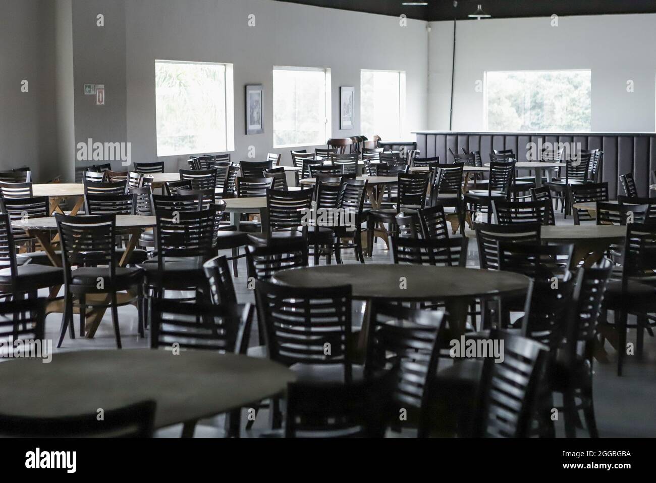 Empty ballroom, with several round tables, no decorations, and dark ...