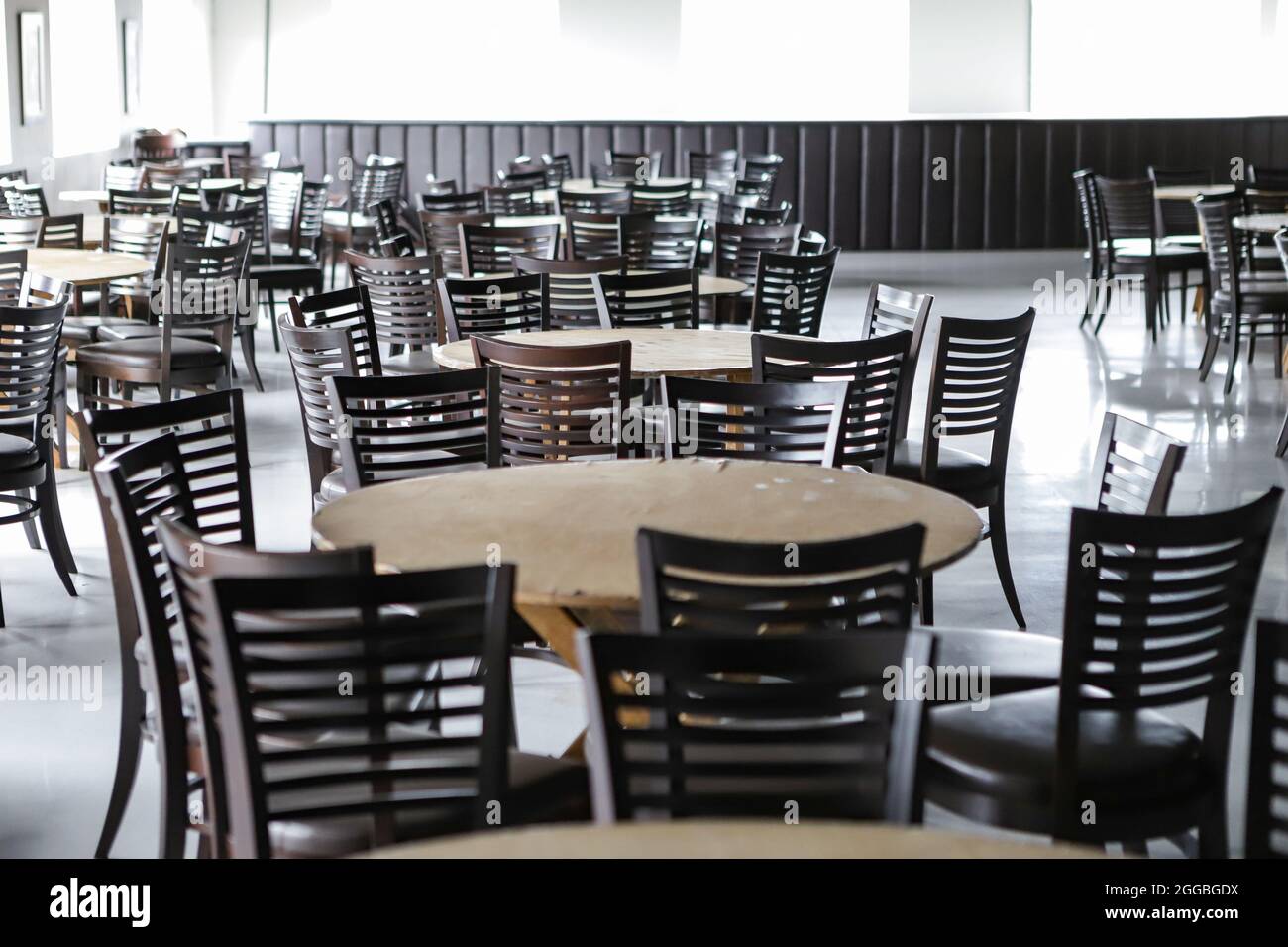 Empty ballroom, with several round tables, no decorations, and dark ...