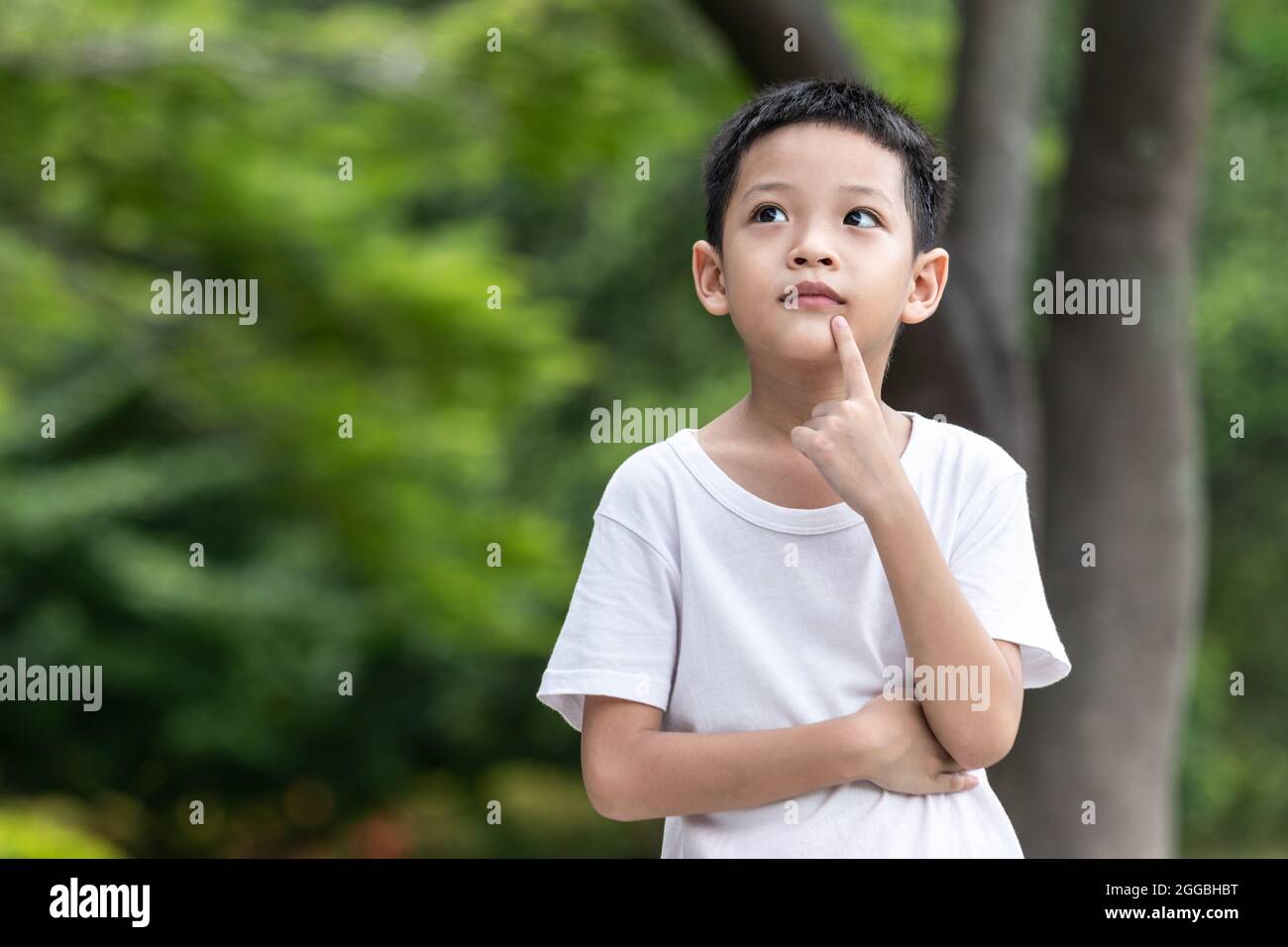 A child wearing a white t-shirt looks smart-looking up in doubt. Little ...