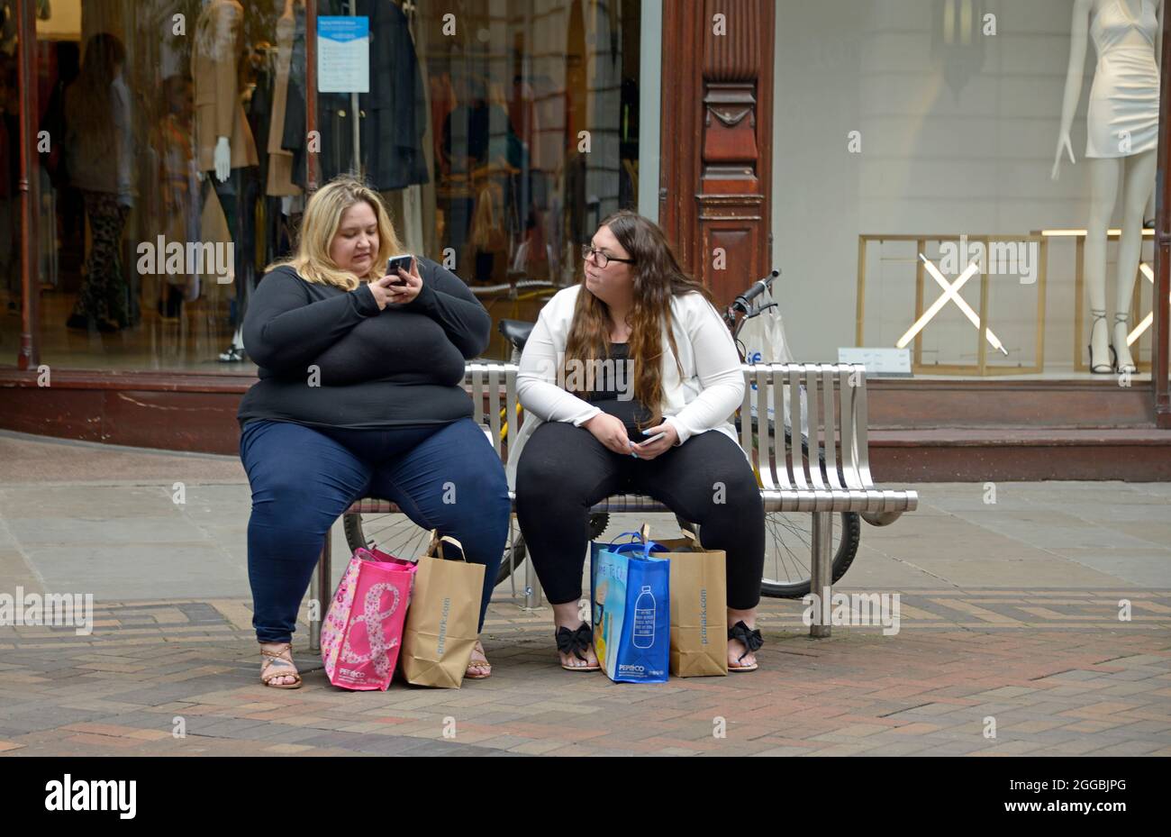 Obese women sat on a bench, after shopping Stock Photo - Alamy
